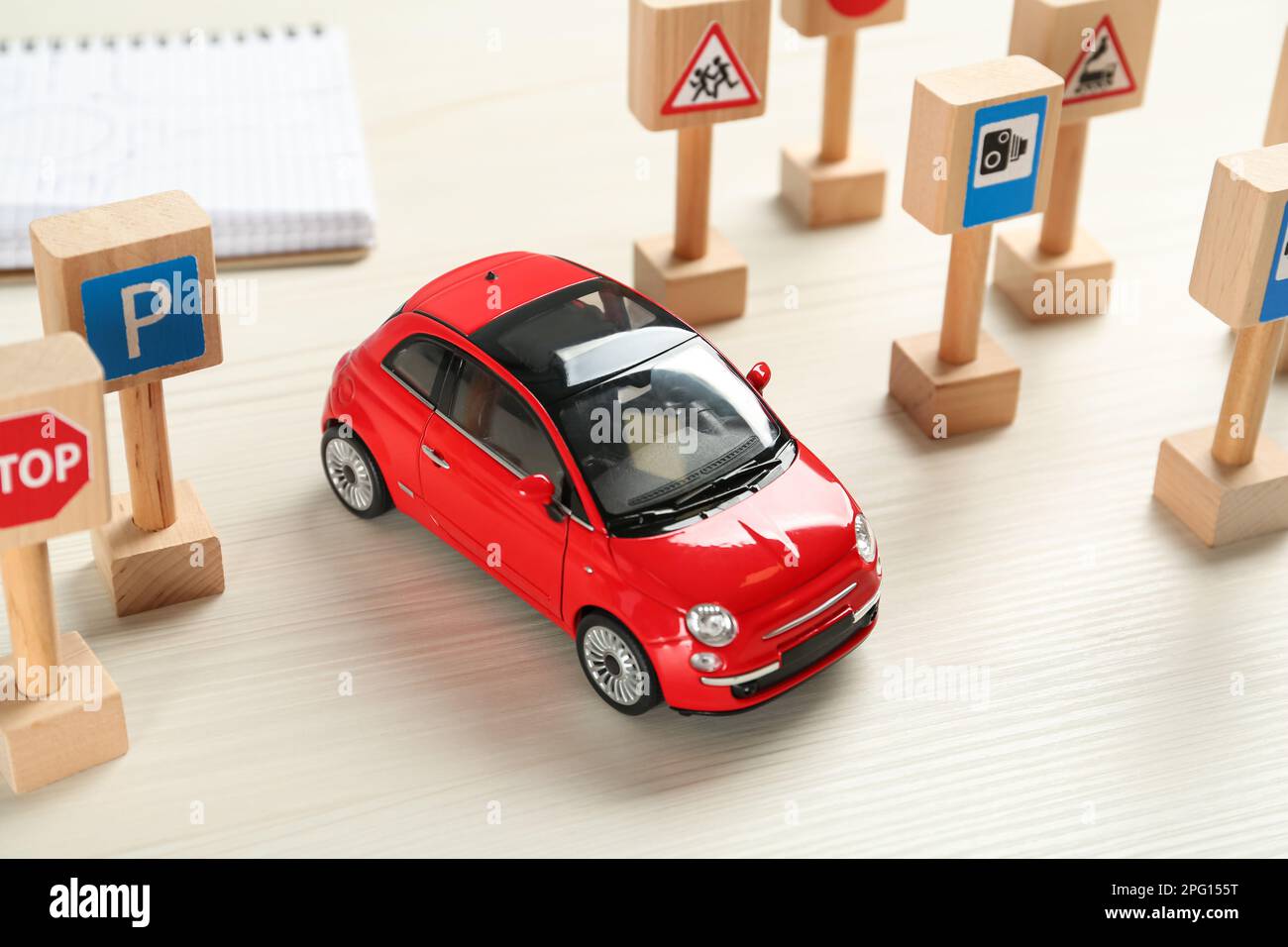 Many different miniature road signs and car on white wooden table ...