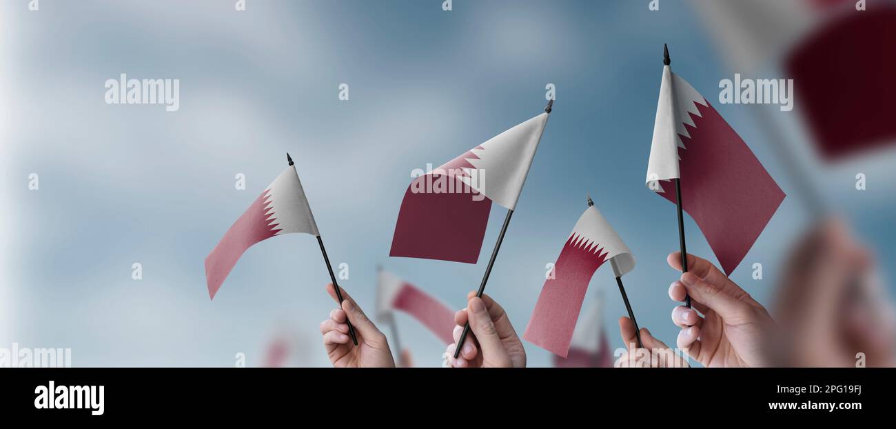A group of people holding small flags of the Qatar in their hands Stock ...