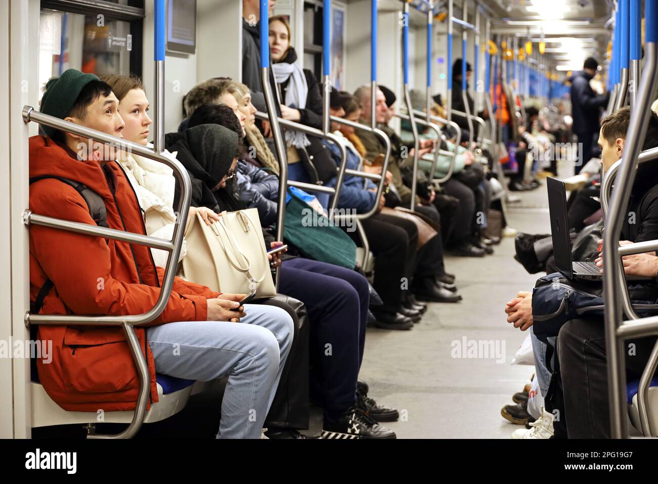 People in a metro train, passengers seating with smartphones. Interior ...