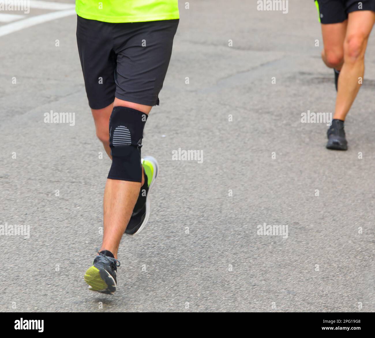runner with kneegiera runs during the running race in the paved road in ...