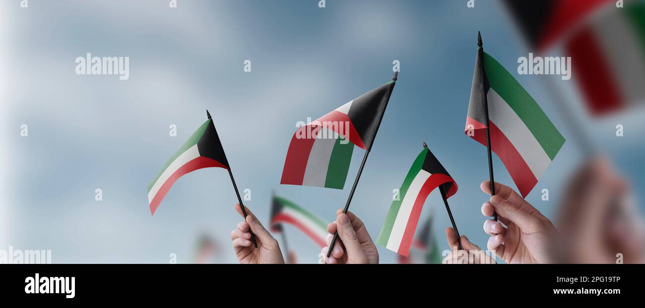 A group of people holding small flags of the Kuwait in their hands ...