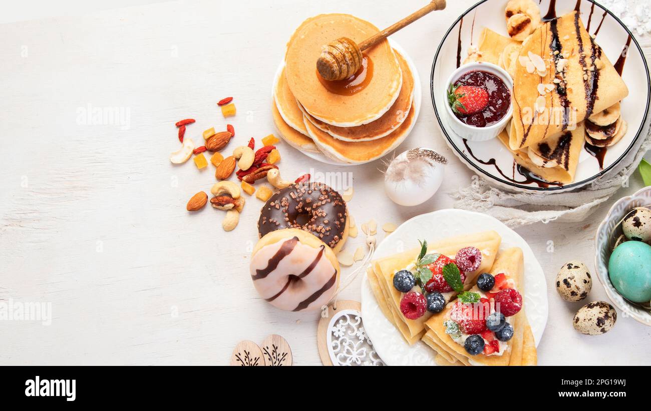 Easter sweet dessert table. Pancakes, crepes, waffles and donuts with ...