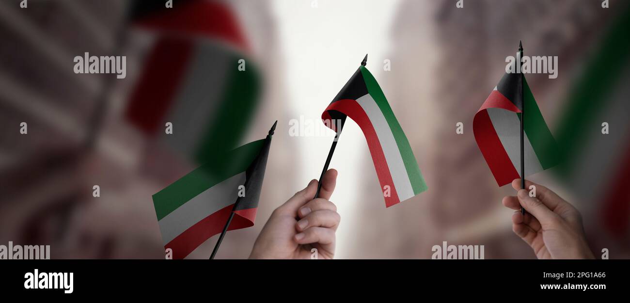 A group of people holding small flags of the Kuwait in their hands ...