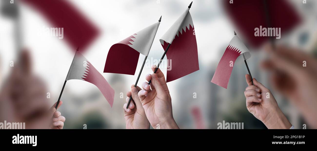 A group of people holding small flags of the Qatar in their hands Stock ...