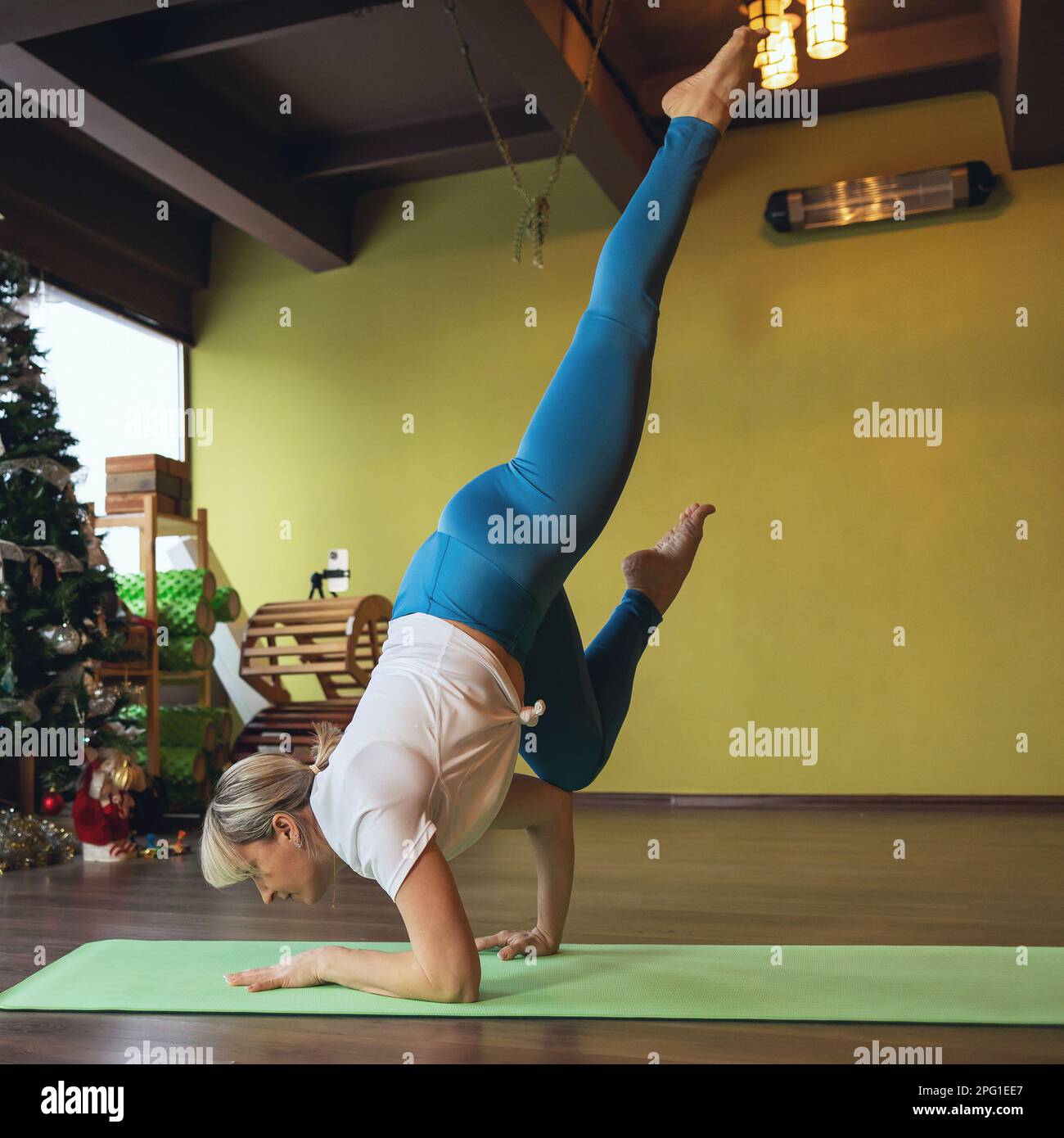 Woman practicing yoga, performing bakasana exercise with leg extended ...