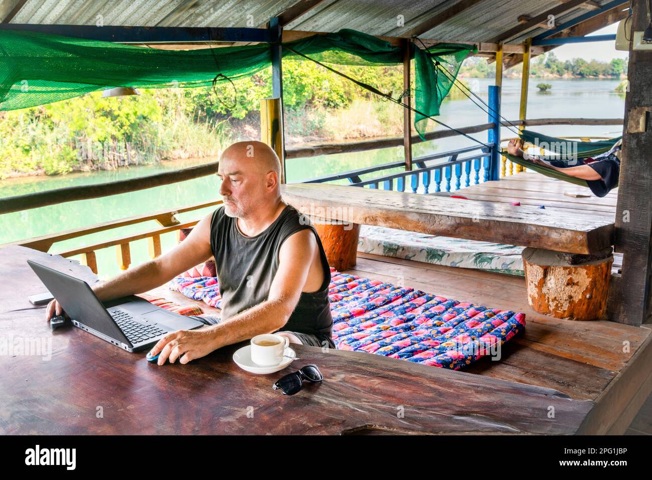 Working remotely on his computer at Si Phan Don,a man traveling the ...