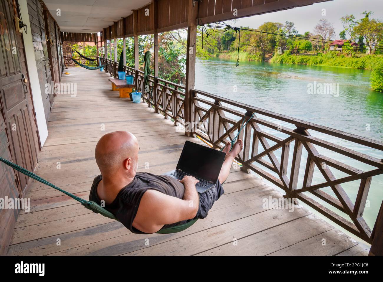 Working remotely on his computer in Si Phan Don,Southern Laos,whilst ...
