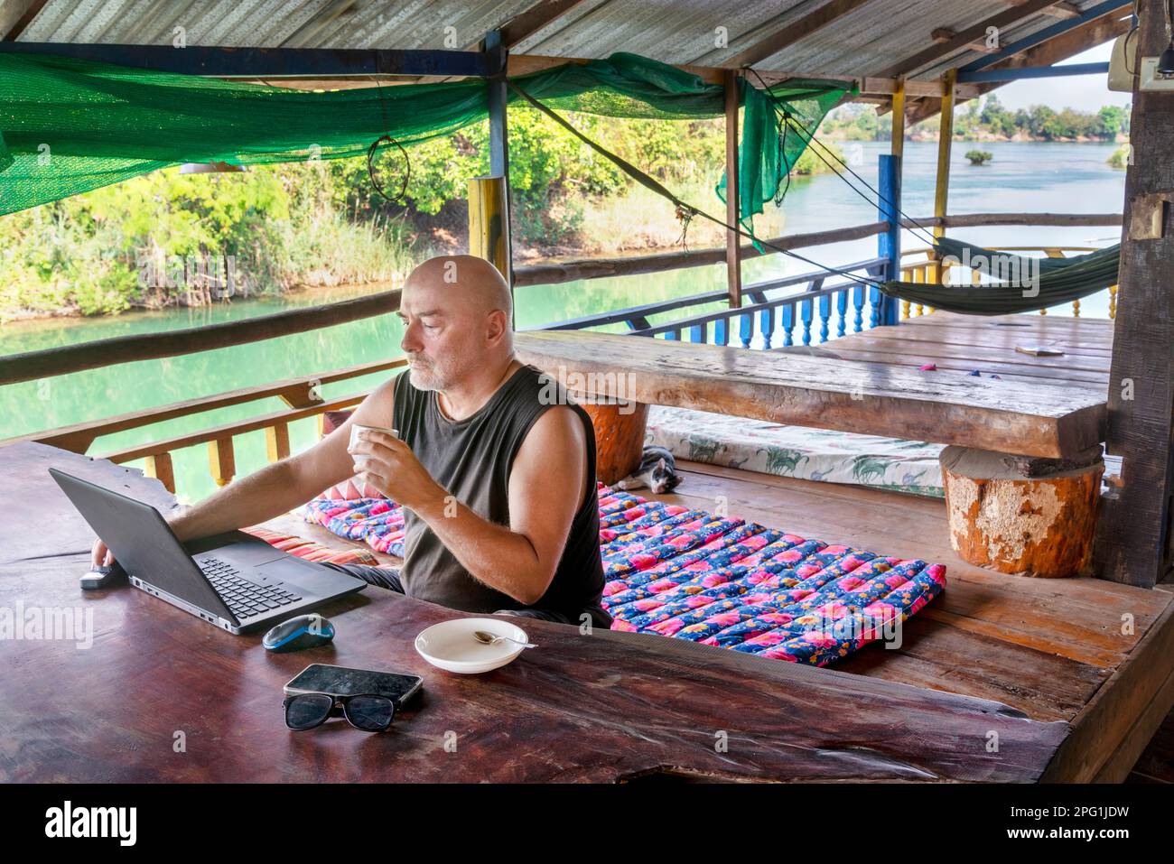 Working remotely on his computer at Si Phan Don,a man traveling the ...