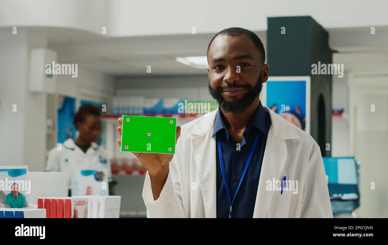 Pharmacy consultant holding greenscreen on box of drugs, showing blank ...
