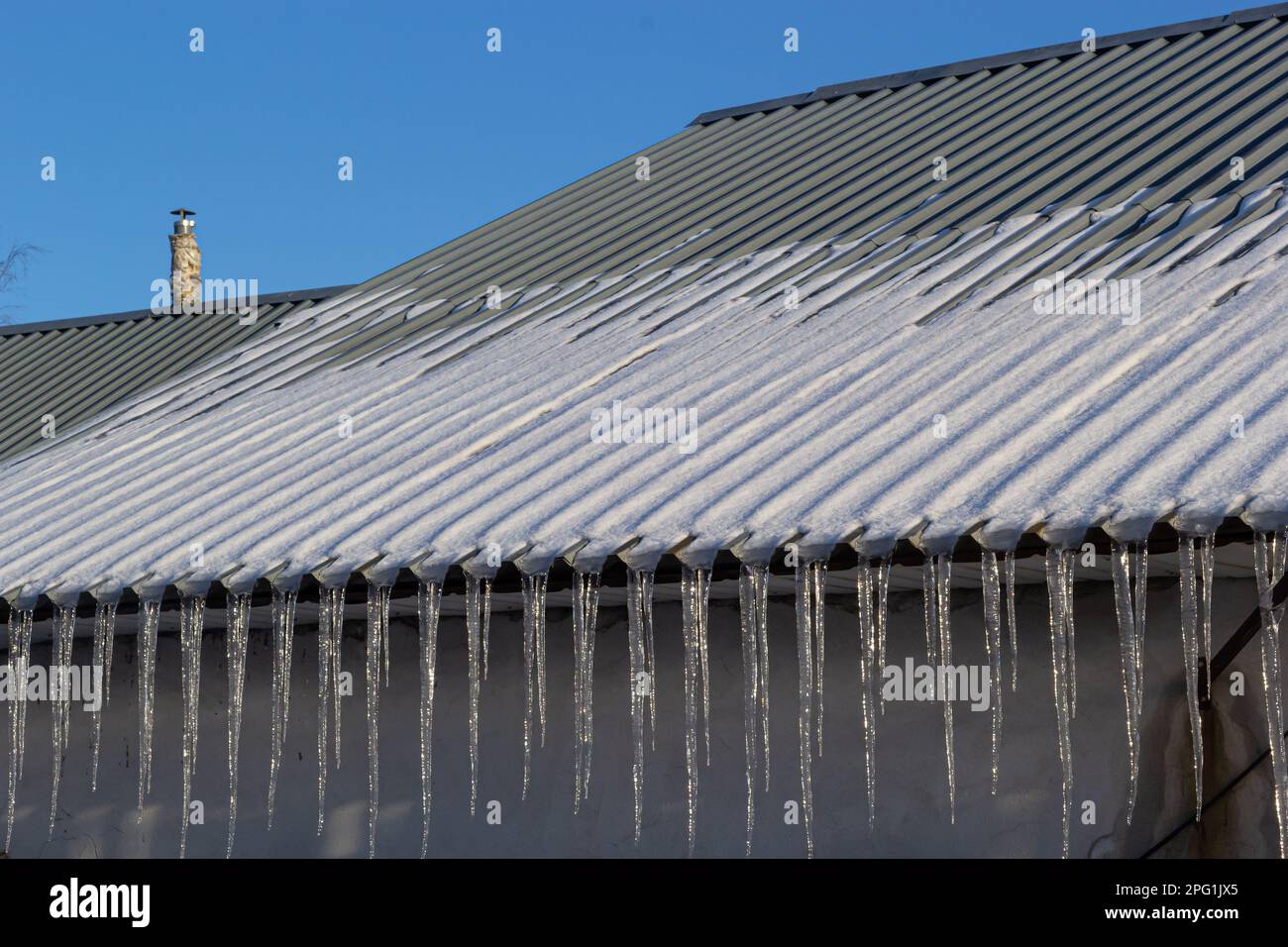 Sharp icicles and melted snow hanging from eaves of roof. Beautiful ...