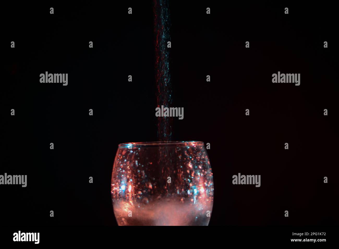 Wine glass filling with liquid on a black background, long exposure ...