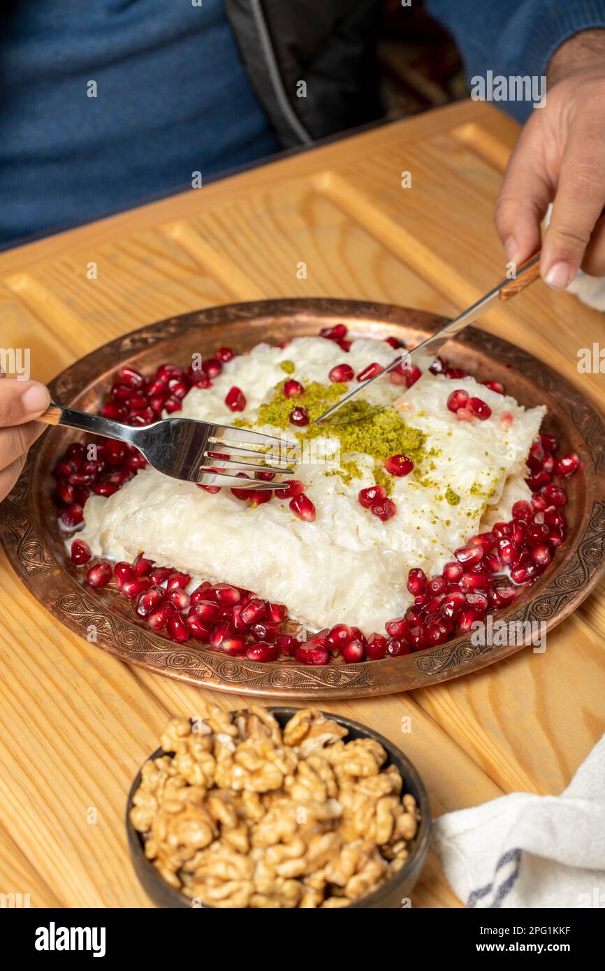 Gullac dessert. Ramadan dessert. Man eating gullac garnished with ...