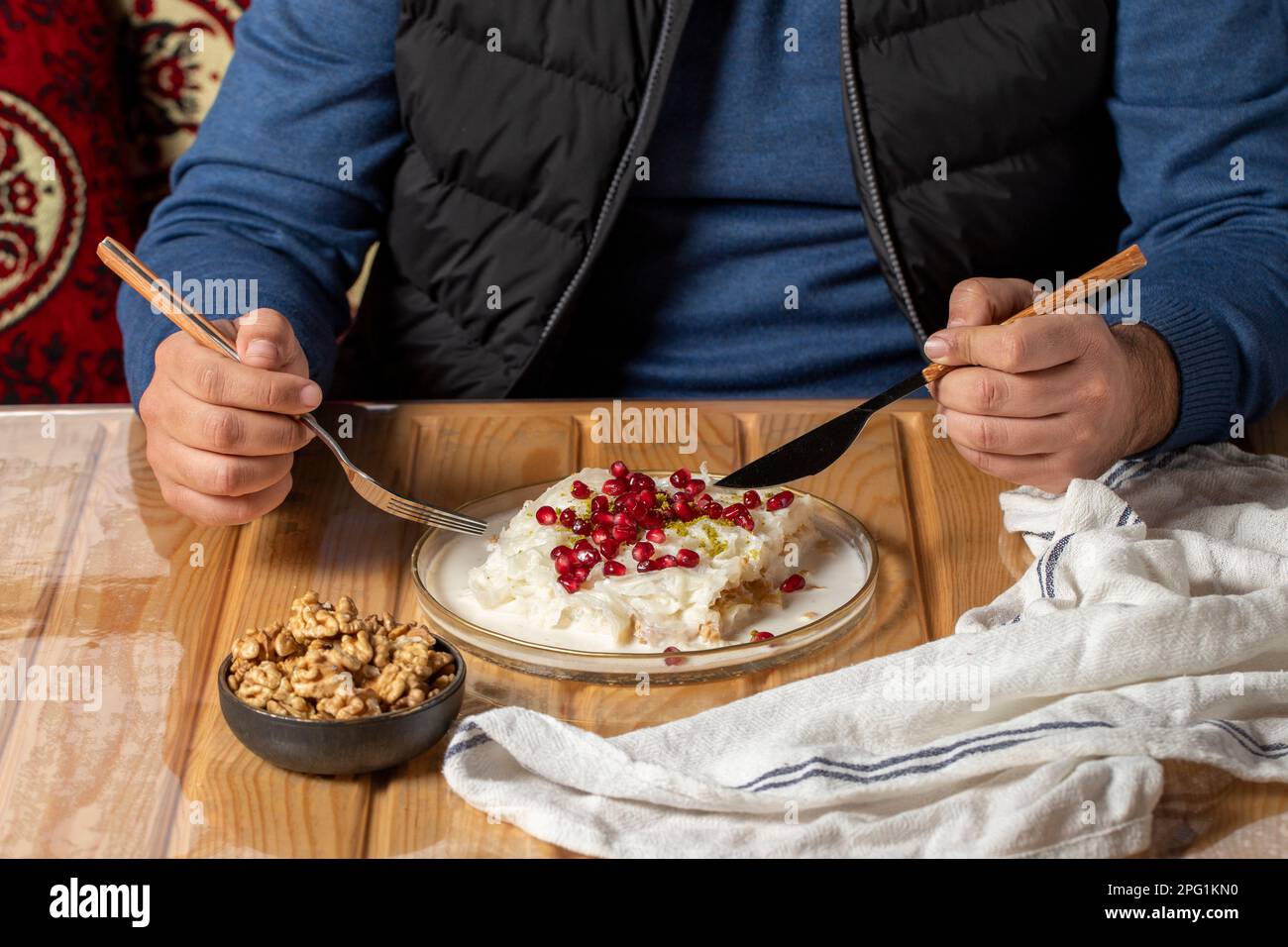 Gullac dessert. Ramadan dessert. Man eating gullac garnished with ...