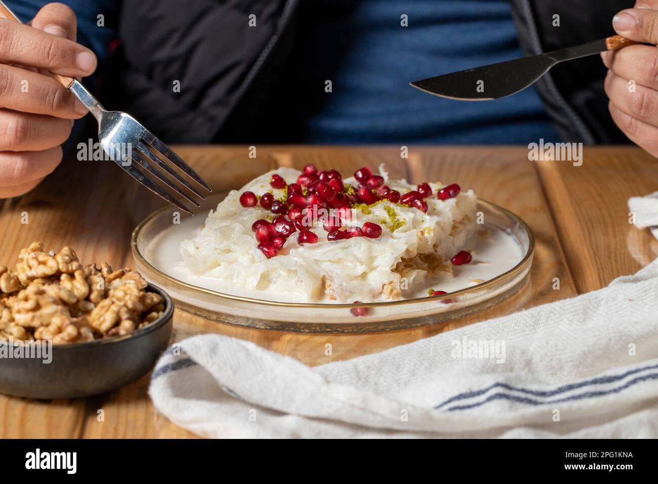 Gullac dessert. Ramadan dessert. Man eating gullac garnished with ...