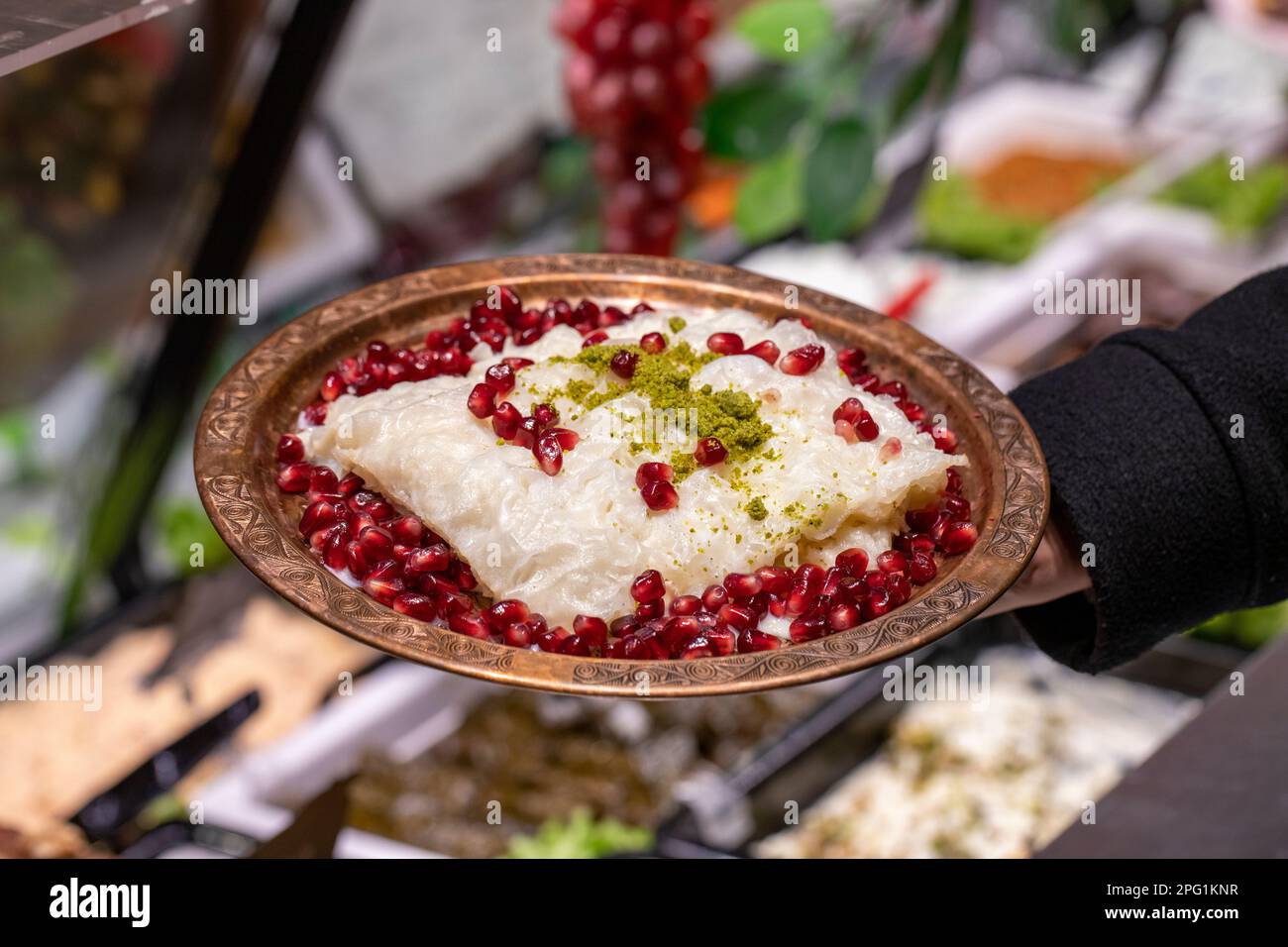 Gullac dessert. Ramadan dessert. Waiter holding gullac garnished with ...