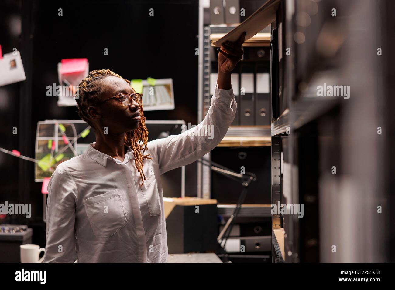 African american woman detective taking csi report file from rack with ...
