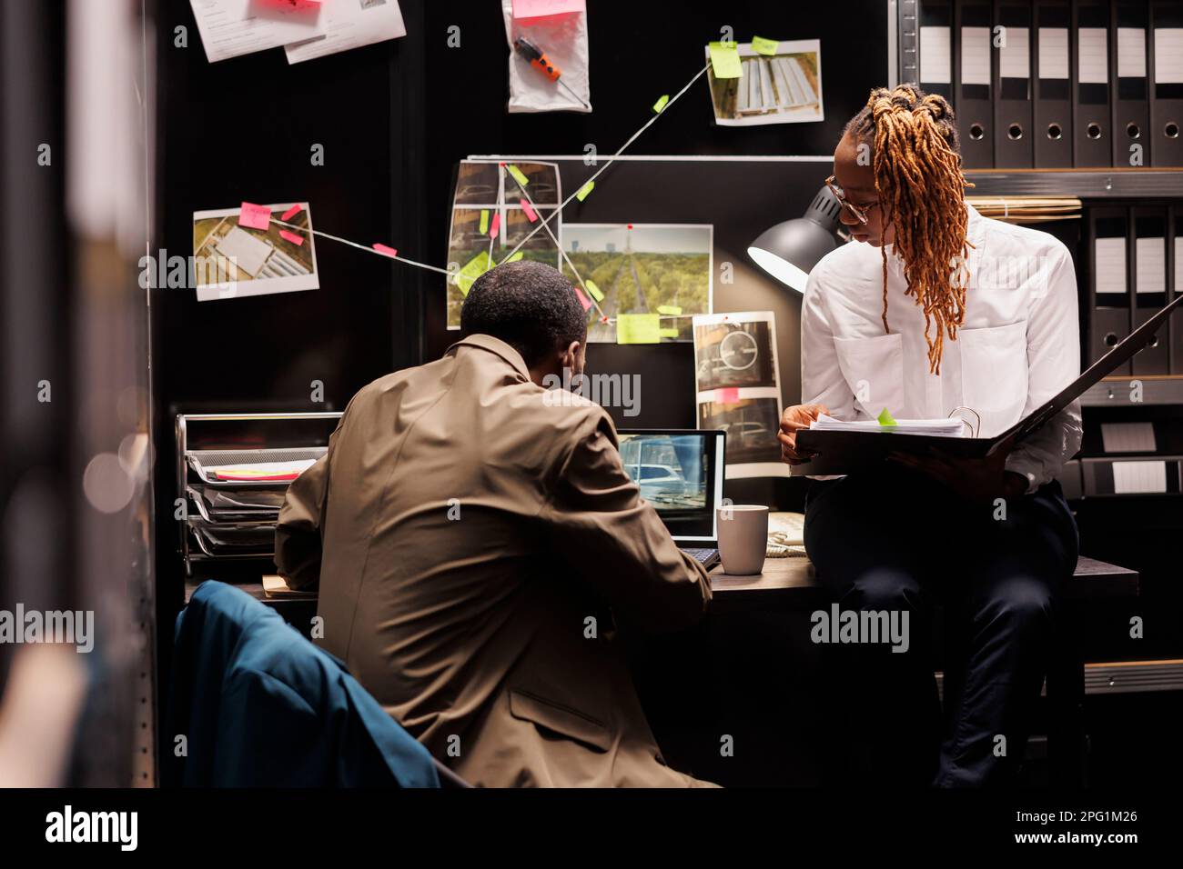 Private investigators analyzing surveillance photos and reading case ...