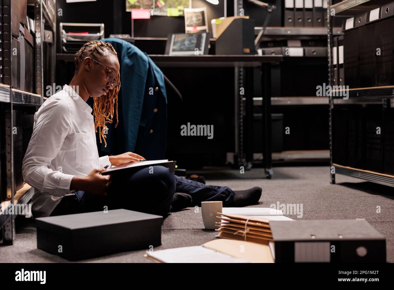 African American Woman Police Detective Reviewing Case File On Floor