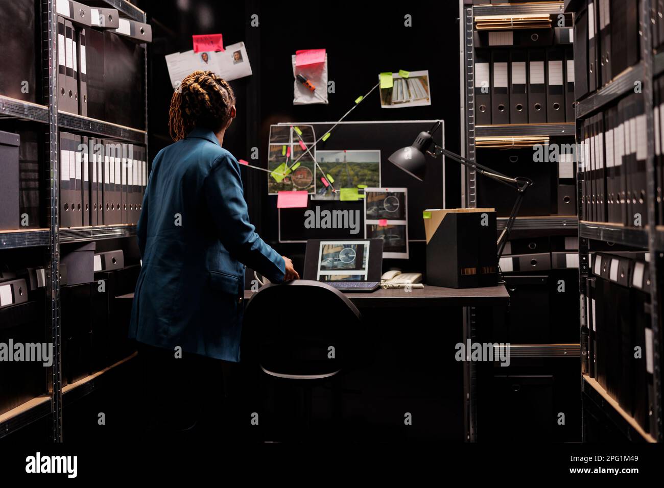 Woman looking at detective board and analyzing crime case evidences ...