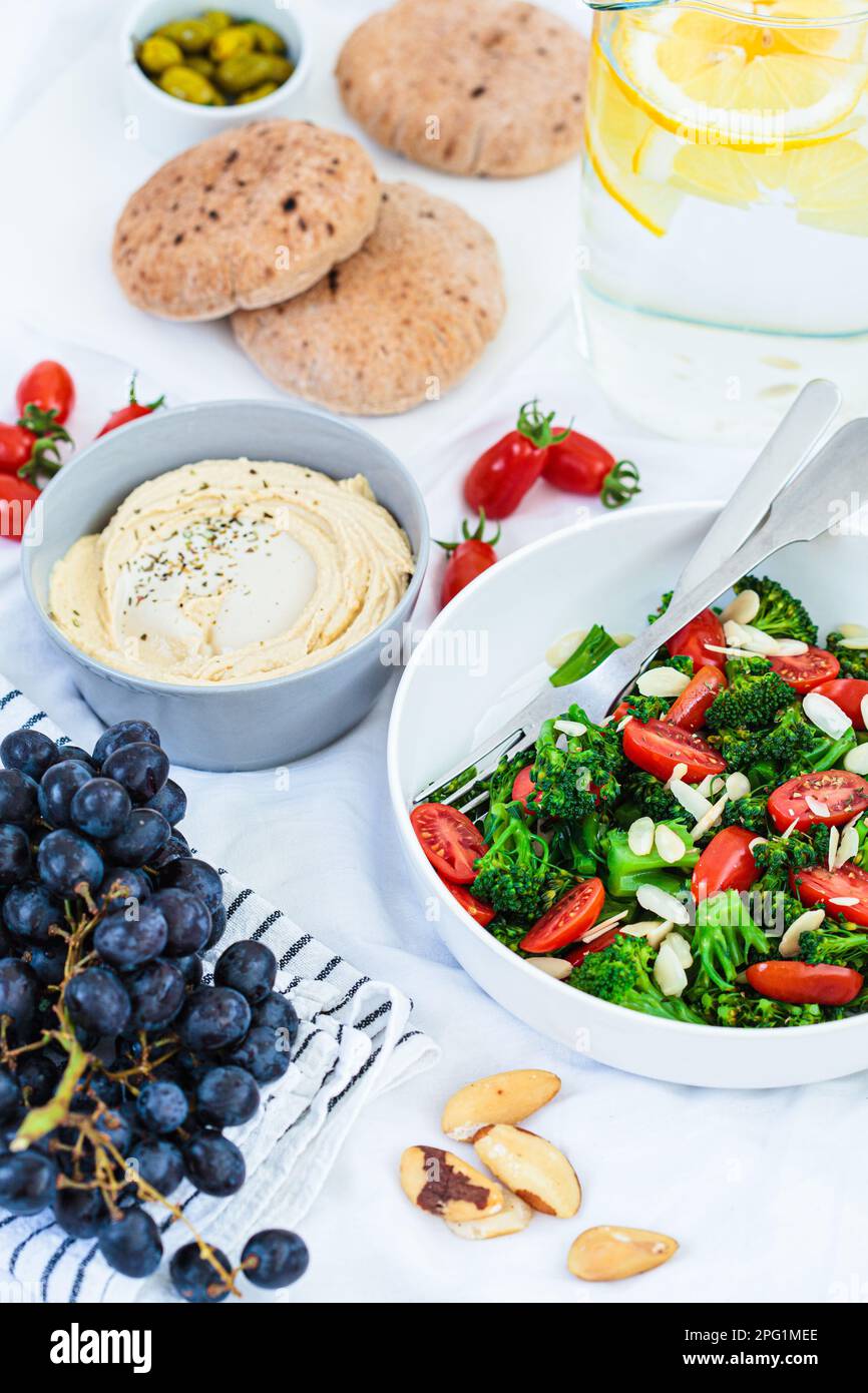 Vegan picnic food: hummus, lemonade, broccoli salad and fruits on a ...
