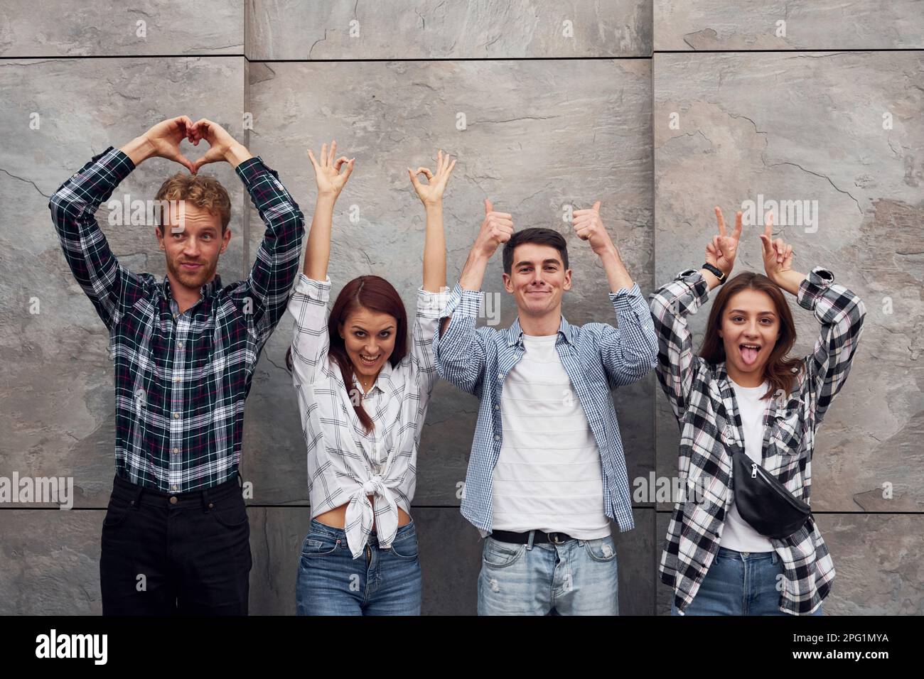 Making different gestures. Group of young positive friends in casual ...