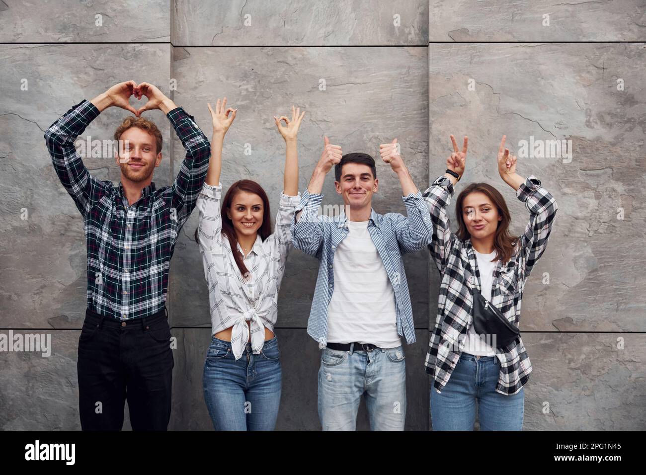 Making different gestures. Group of young positive friends in casual ...