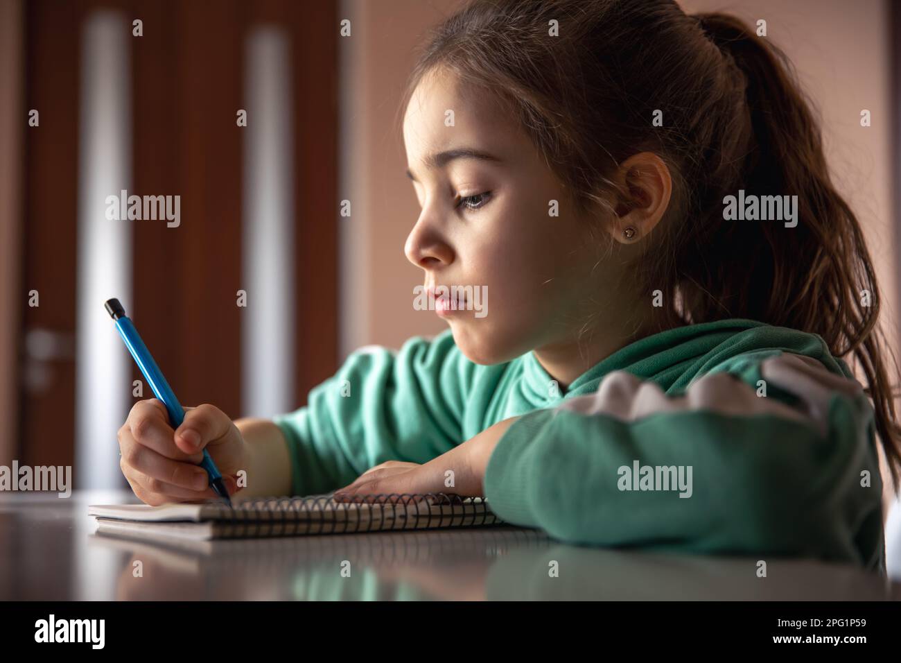 Serious little girl writes with a pen in a notebook Stock Photo - Alamy