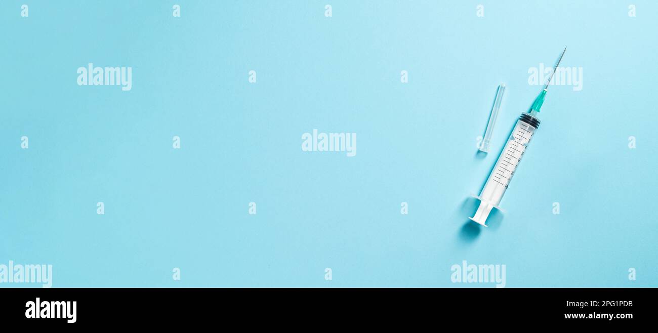 Transparent plastic syringe on blue background with empty copy space ...