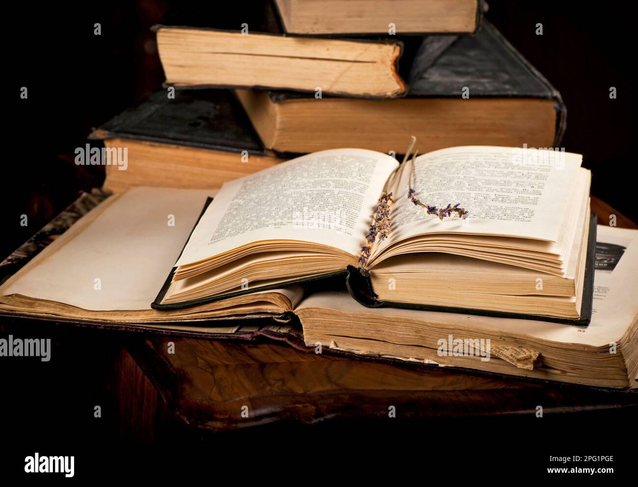 a stack of old books with bookmarks on a wooden background. A sprig of ...