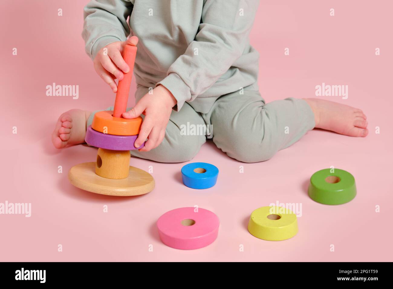 Happy toddler baby plays with a pyramid on a studio pink background ...
