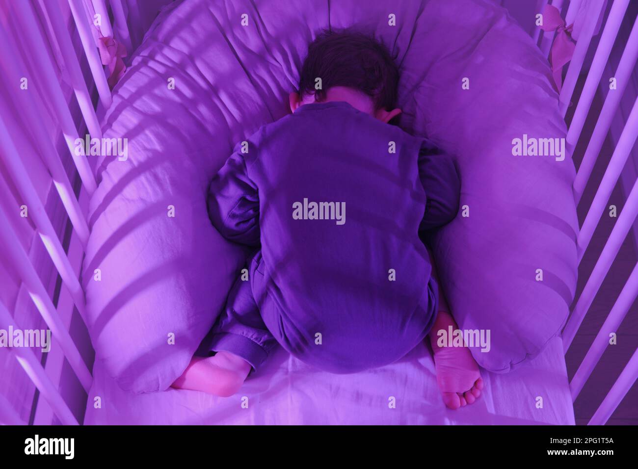 Toddler baby sleeps face down on his stomach while lying in a crib ...