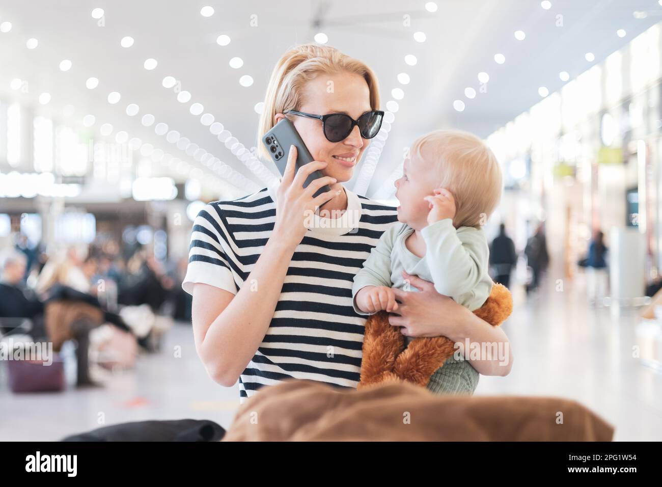 Mother talking on mobile phone while traveling with child, holding his ...