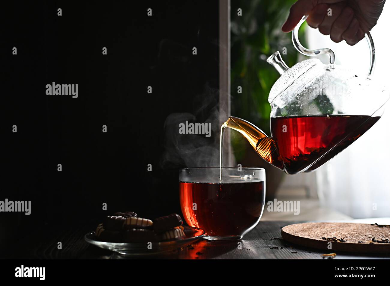 A woman's hand pouring tea into a mug. Steamed tea, morning tea, home ...