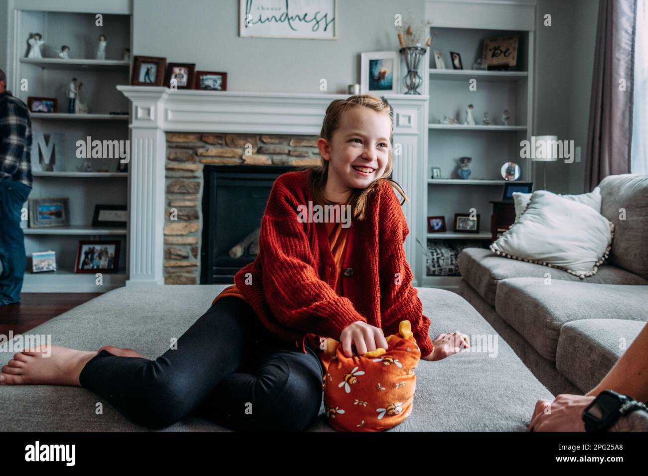 Happy young girl sitting on couch inside Stock Photo - Alamy