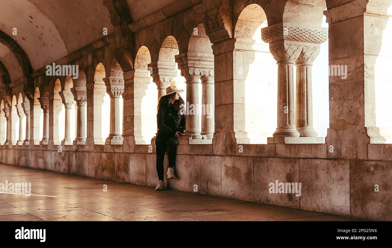 girl sitting with hat in corridor with architectural windows Stock ...