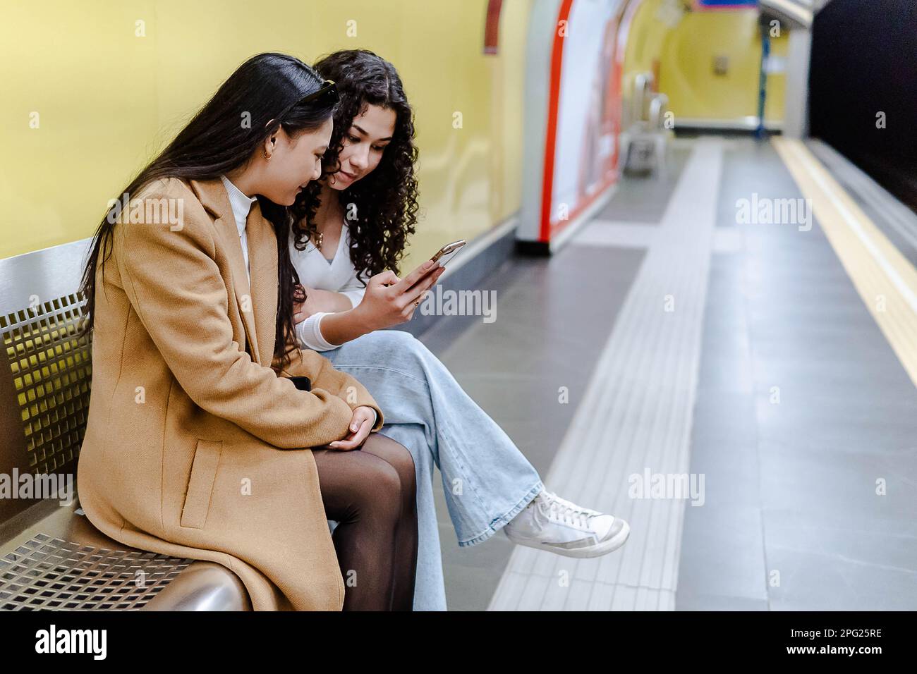 stock photo of two girls using the mobile in the subway Stock Photo - Alamy