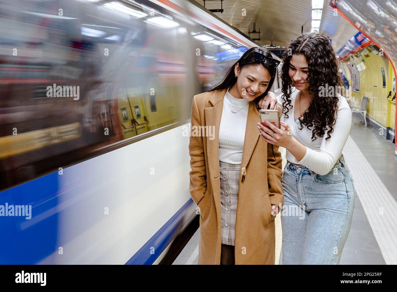 stock photo of two girls using the mobile in the subway Stock Photo - Alamy