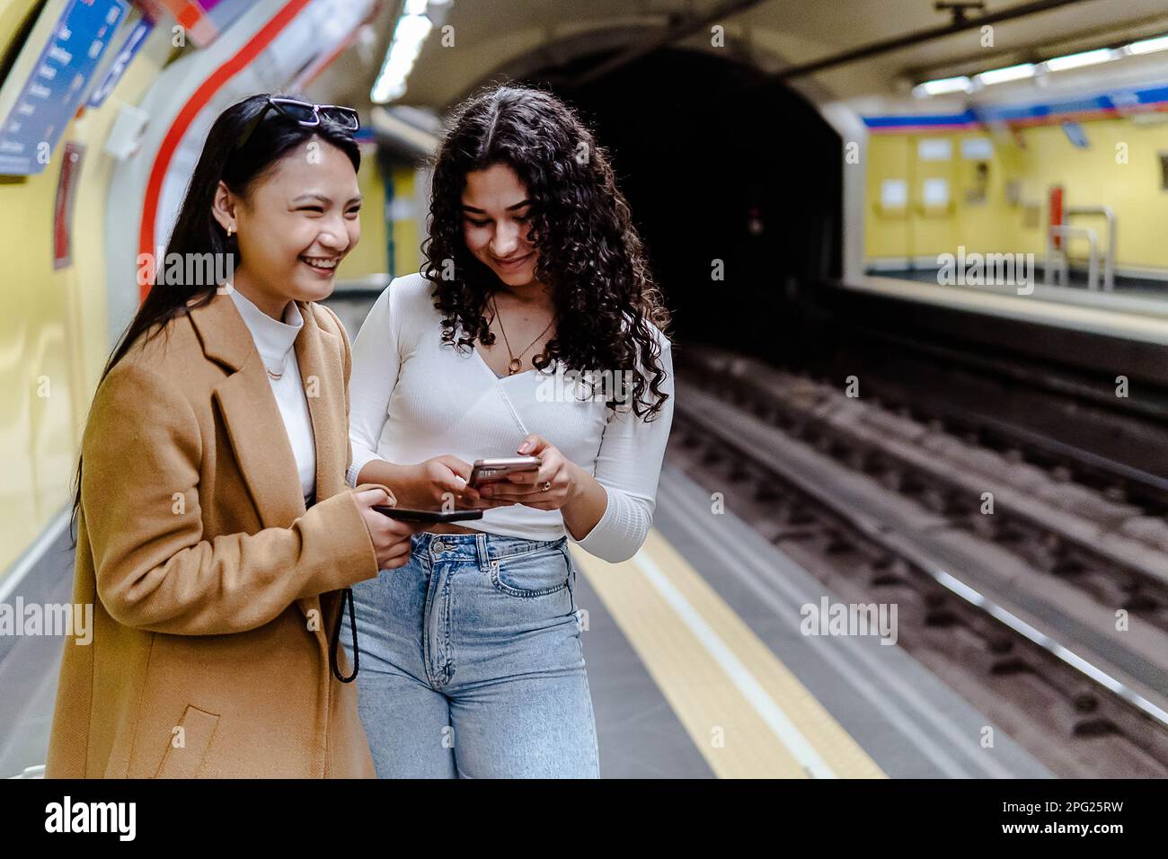 stock photo of two girls using the mobile in the subway Stock Photo - Alamy