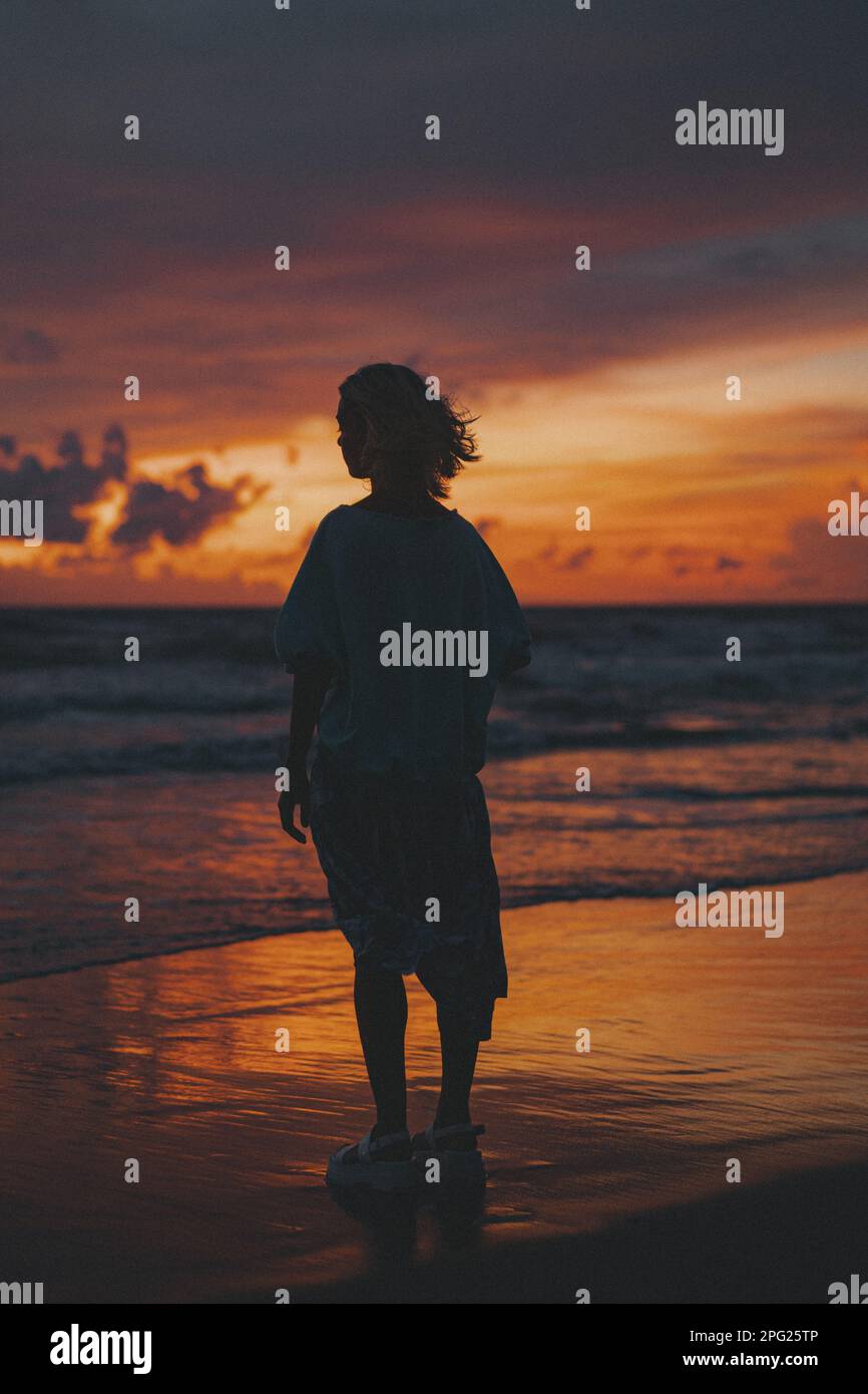 Woman on the ocean watching the sunset. Film, grain Stock Photo - Alamy