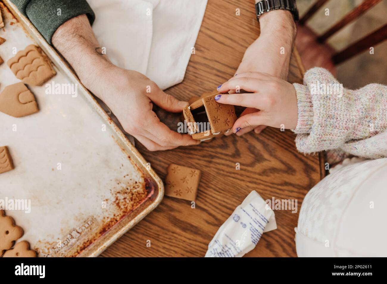 Father and daughter work together to build gingerbread house Stock ...