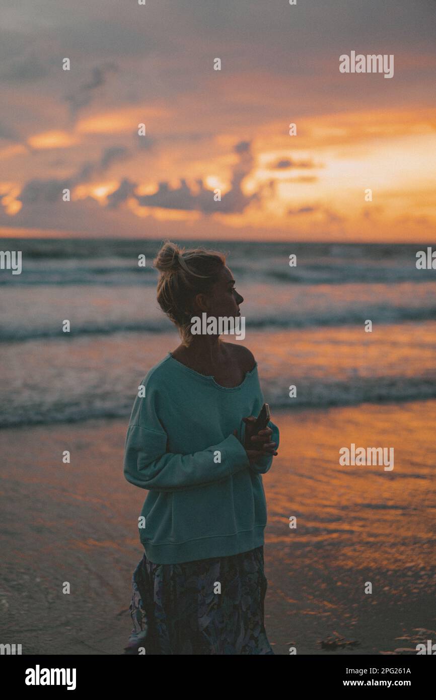 Woman on the ocean watching the sunset. Film, grain Stock Photo - Alamy