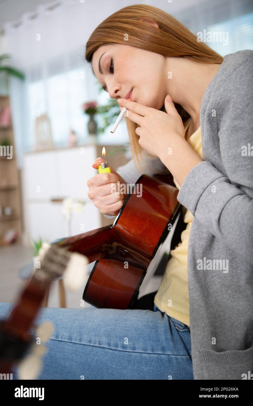 woman sitting smoking and playing guitar at home Stock Photo - Alamy