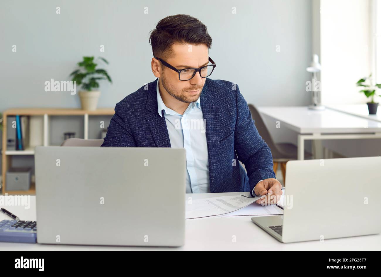 Focused businessman using two laptop computers in office Stock Photo ...