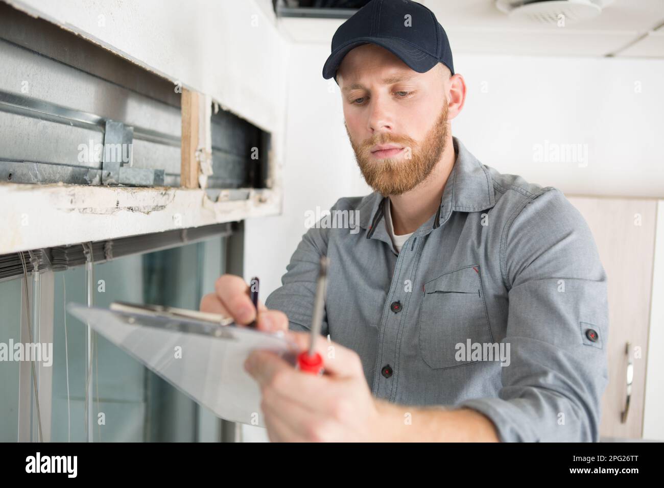 home inspector on a ladder while writing on a clipboard Stock Photo - Alamy