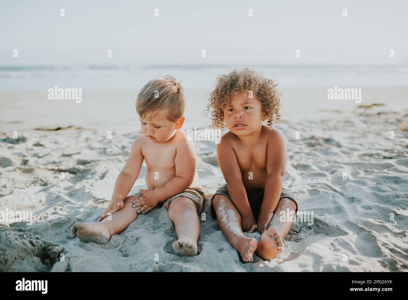 Mixed race toddler boy twins sitting and playing in sad Stock Photo - Alamy