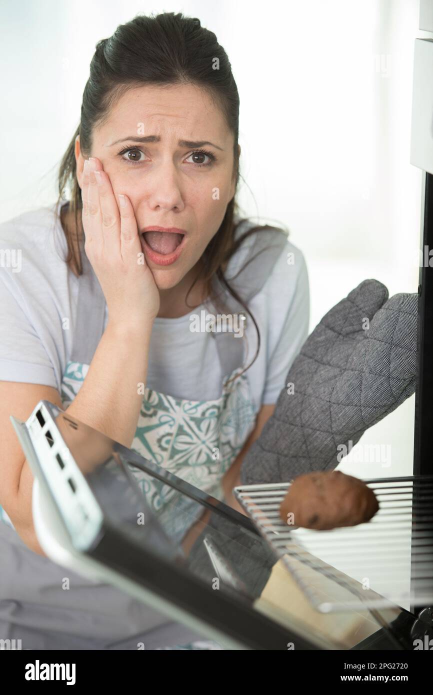 woman looking with dismay at burnt food in the oven Stock Photo - Alamy