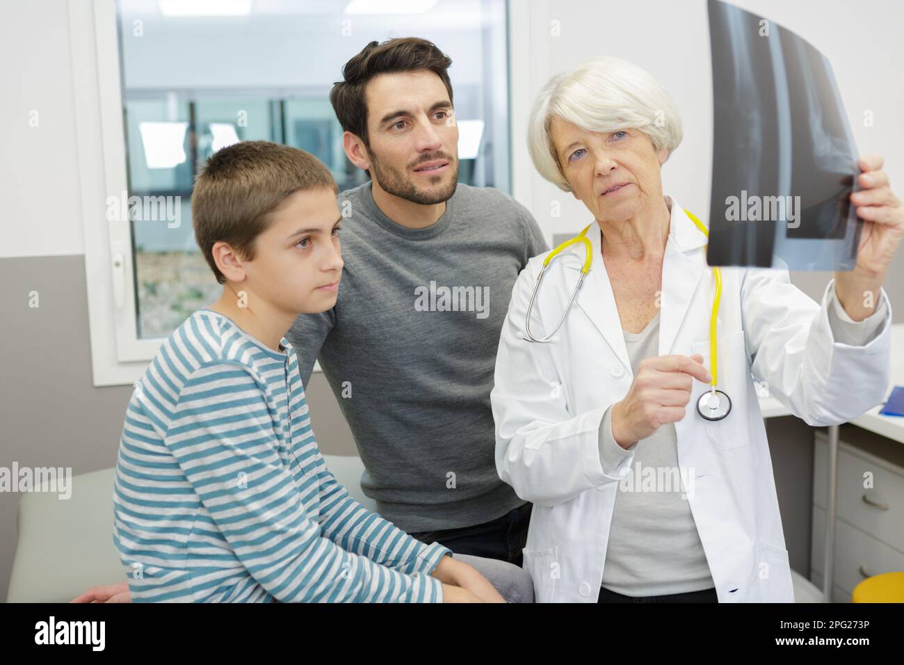 senior doctor showing xray to boy and dad Stock Photo - Alamy