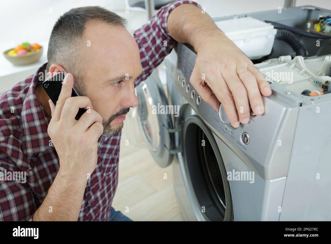 man loading clothes into washing machine in kitchen Stock Photo - Alamy