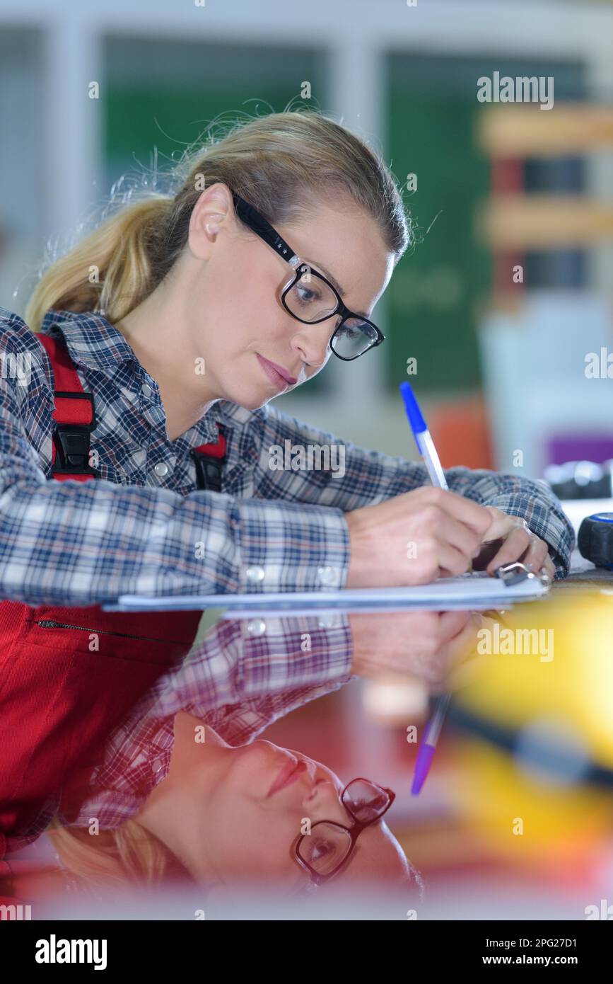 female manual worker writing on clipboard in reflective surface Stock ...