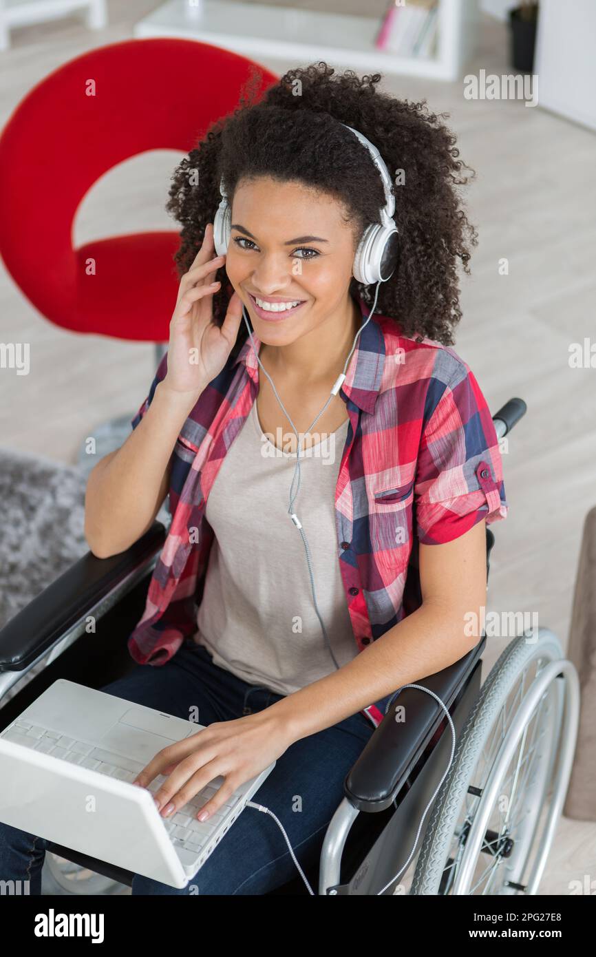 young disabled girl in wheelchair using laptop and headphones Stock ...